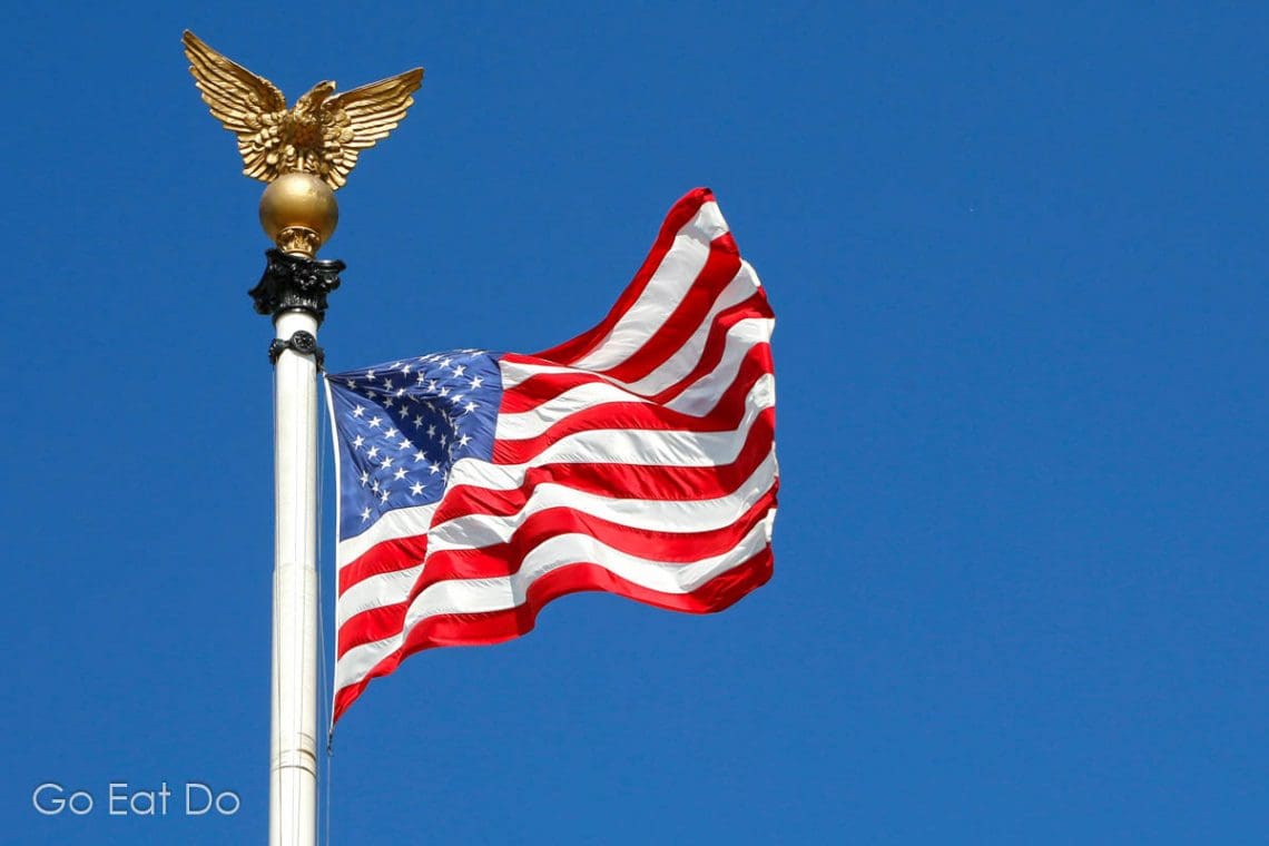A golden eagle tops a flagpole from which the Stars and Stripes flies ...
