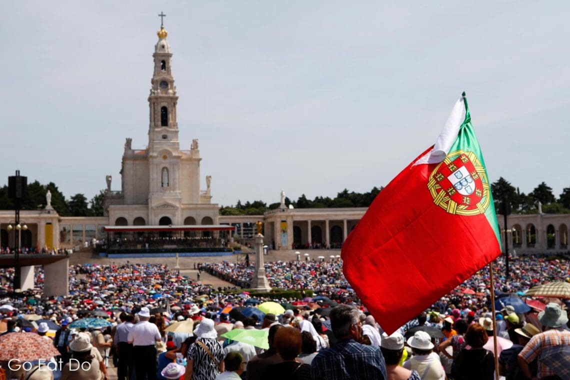 A Portuguese flag flies above pilgrims gathered in front of the ...